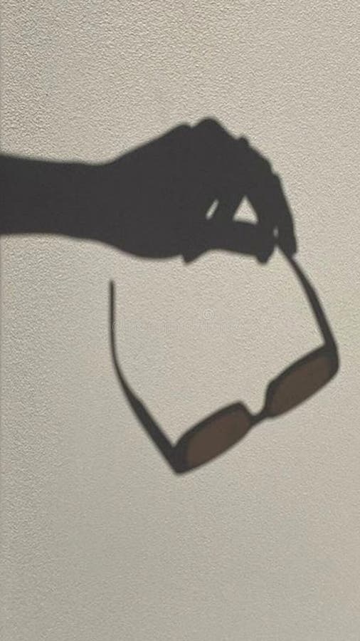 Hand Shadow Holding Sunglasses Against Textured Wall Creative Shadow ...