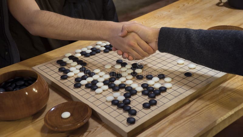 Hand Playing Black and White Stone Pieces on Chinese Go or Weiqi Game ...