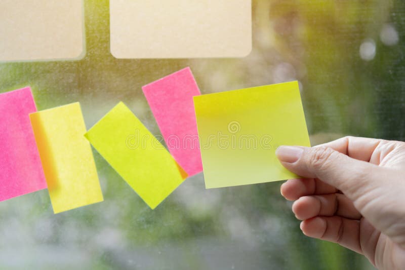 A Hand Shoots Multi-Colored Square Post-it Notes Pasted on a Glass Wall ...