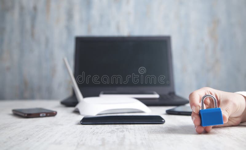 Hand Showing Padlock. Smartphones, Internet Router, Laptop on the Desk ...