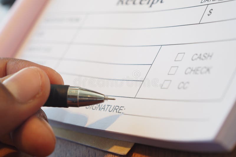 Hand Signing a Detailed Receipt Using a Pen Positioned on a Wooden ...