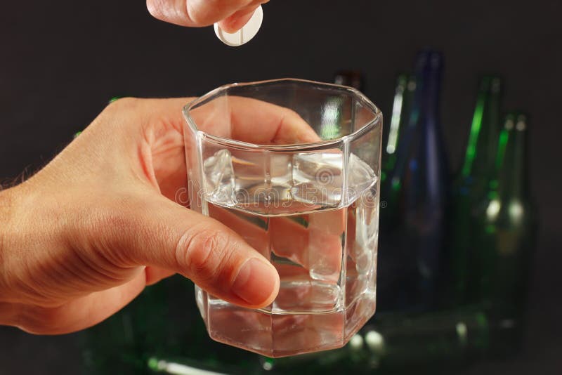 Hand with a Soluble Tablet from Hangover Over a Glass of Water on Dark ...