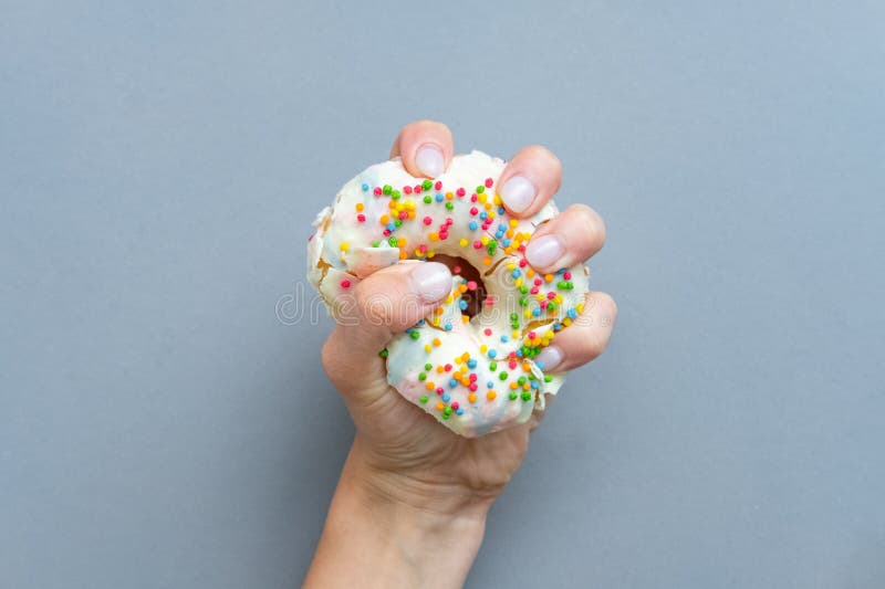 Hand Squeezes the Doughnut. One Donut with White Icing. an Overhead ...