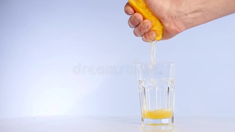 Hand Squeezing Juice of Orange into Glass of Water in Slow Motion Stock ...