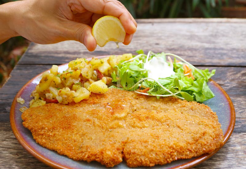 Hand Squeezing a Slice of Lemon on Fried Schnitzel Stock Photo - Image ...