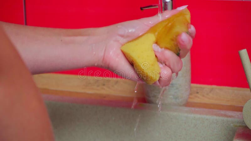 Hand is Squeezing a Soft Sponge at the Kitchen Sink for Effective ...
