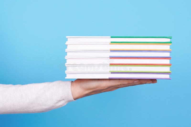 Hand with Stack of Books on Blue Background Stock Image - Image of ...