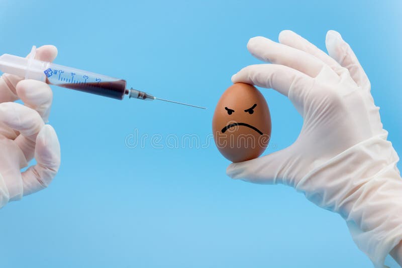 A Hand with a Syringe Makes an Injection into the Egg Close-up. the ...