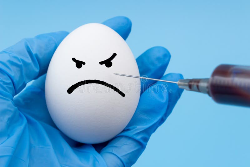 A Hand with a Syringe Makes an Injection into the Egg Close-up. the ...