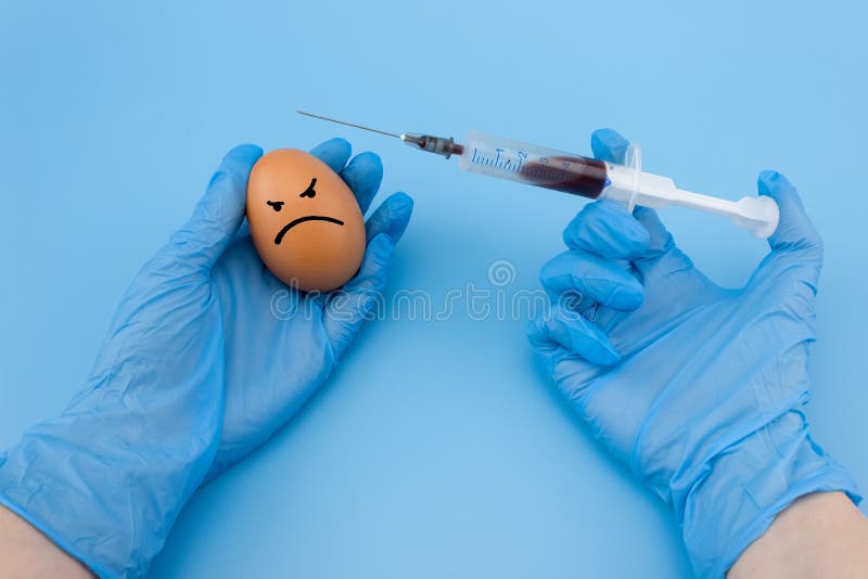A Hand with a Syringe Makes an Injection into the Egg Close-up. the ...