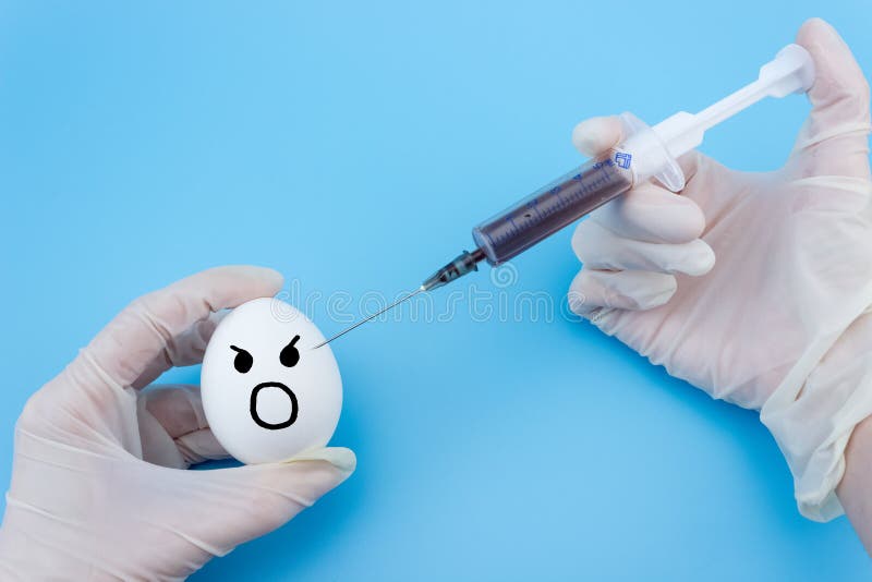 A Hand with a Syringe Makes an Injection into the Egg Close-up. the ...
