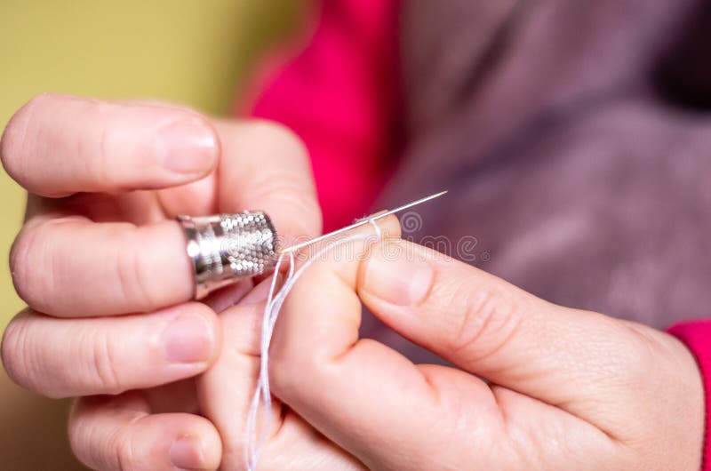 A Hand with Thimble Knotting and Cutting a Thread on a Needle in a ...