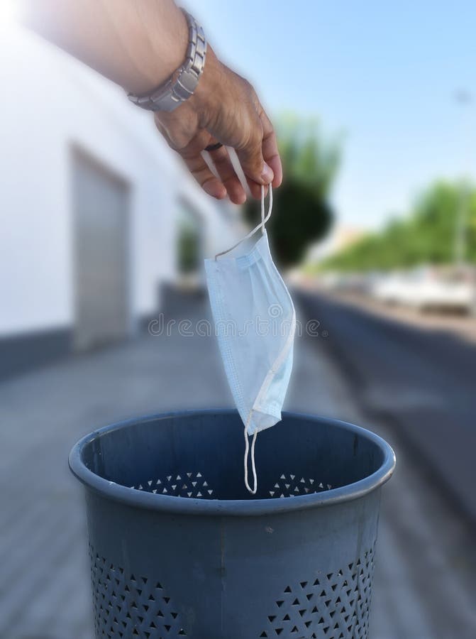 Hand Throwing a Mask into a Trash Can in the Street with Brightness ...