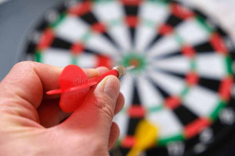 A Hand Throws Darts on a Dartboard, a Hand Holding a Dart, a Colorful ...