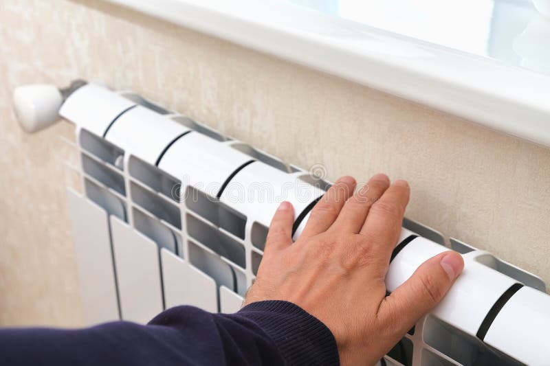 A Hand Touching a Warm Home Radiator, Highlighting the Cozy and Energy ...