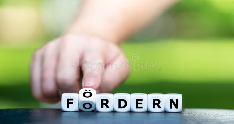 Hand Turns Dice and Changes the German Expression `fordern` Demand To `foerdern` Support. Stock ...