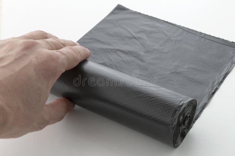 Hand Unwinds a Roll of Plastic Garbage Bags, a Black Polyethylene Waste ...
