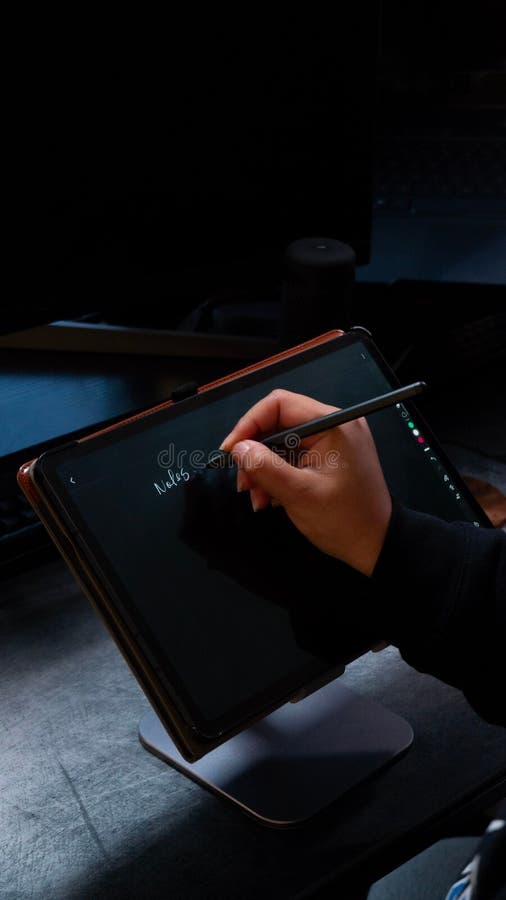 Hand Using a Digital Pen on a Tablet Writing Notes. Low Light Stock ...