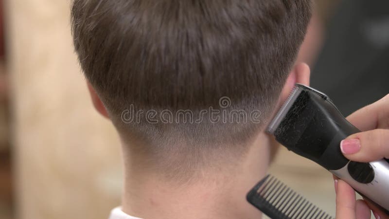 A Hand with a Clipper Cuts the Boy S Hair. Shaves His Temples and the ...