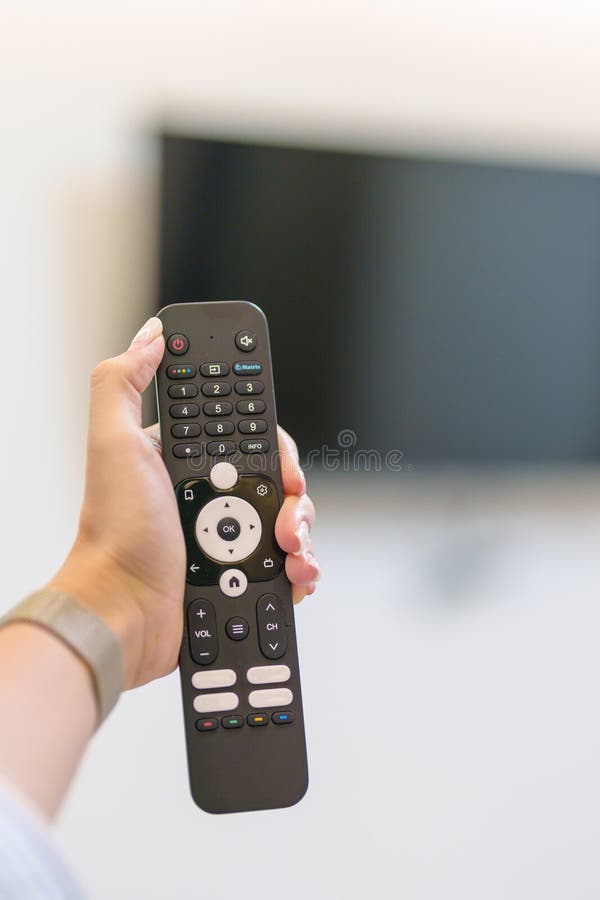 Hand Using Remote Controller Press Button for Adjust Smart TV in Modern Room at Home. Woman ...