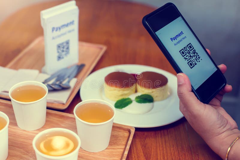 Hand Using Smart Phone To Scan QR Code on Tag with Blurry Dessert and ...