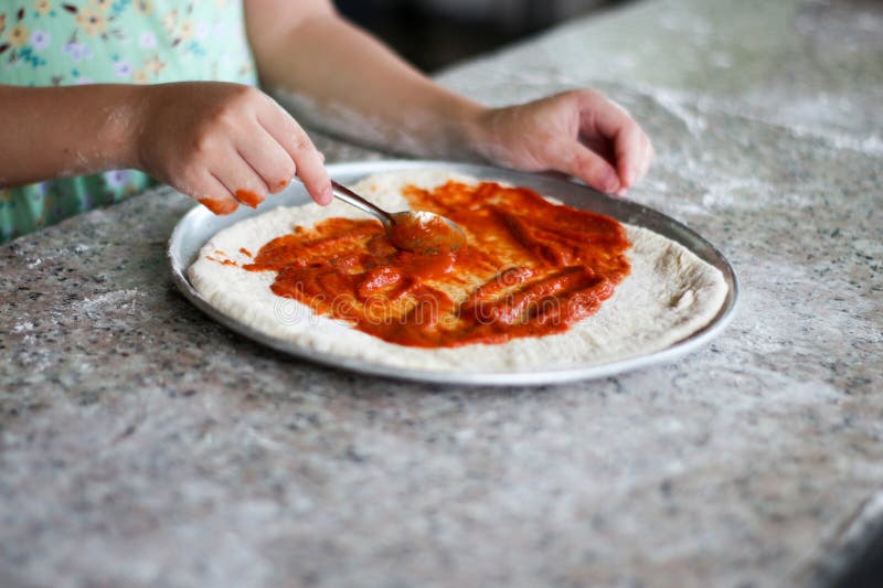A Hand is Using a Spoon To Spread the Cream into the Dough To Make a ...