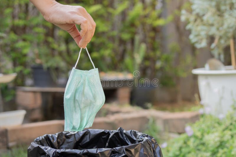 Hand of Woman Holding Protective Mask Over Garbage Bin in the Park with ...