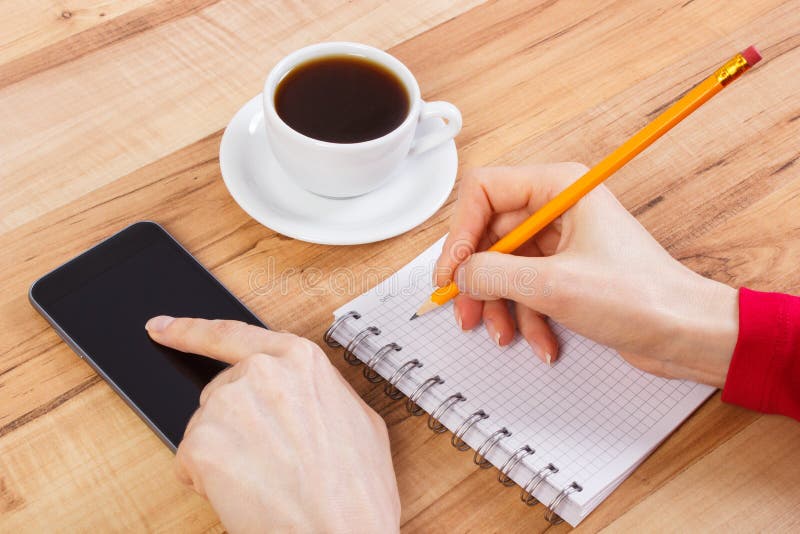 Hand of Woman Using Mobile Phone and Writing Notes in Notepad, Cup of ...