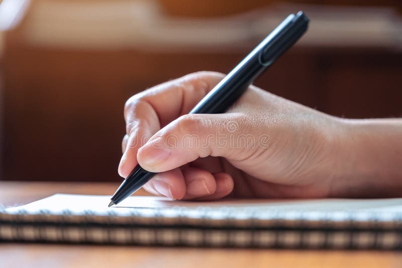 A Hand Writing Down on a White Blank Notebook on Wooden Table Stock ...