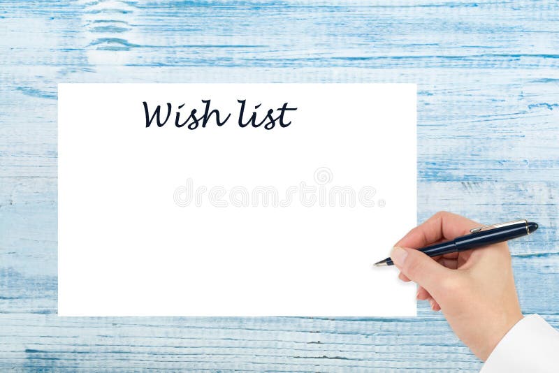 A Hand is Writing on a Paper on a Wooden Table. Make Wish List, Notes ...