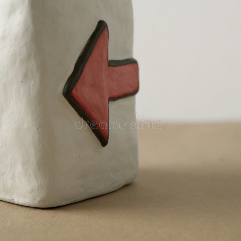 Handcrafted Clay Block with a Red Arrow Symbol on a Neutral Background ...