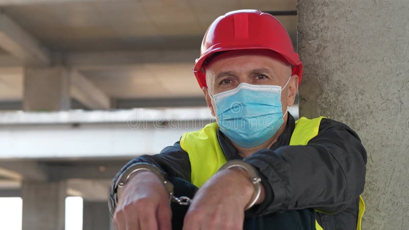 Handcuffed Builder in Face Mask Sits at Construction Site and Looks at ...