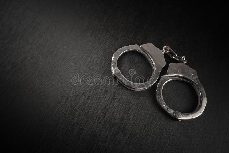Handcuffs on a Black Table with a Light in the Middle Stock Photo ...