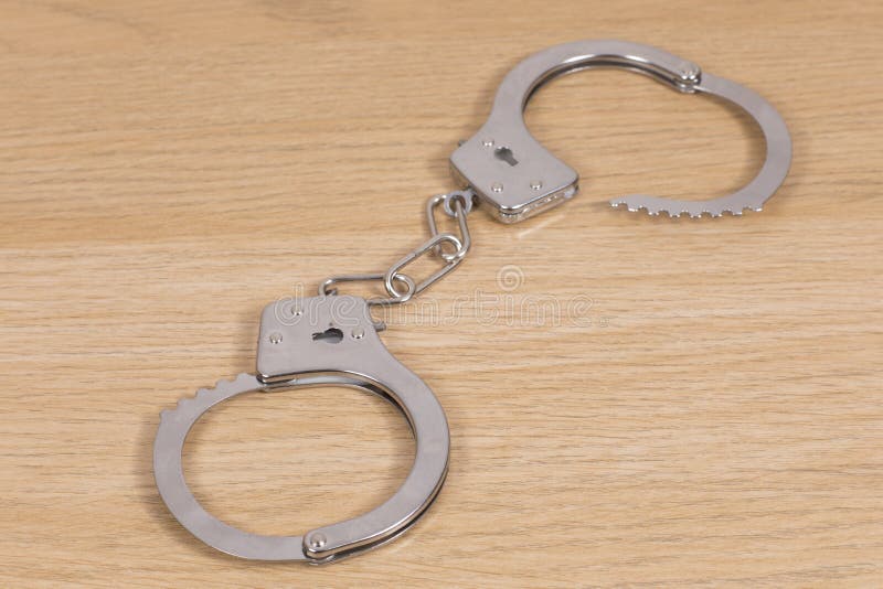 Handcuffs on wooden desk stock photo. Image of busted - 97344896