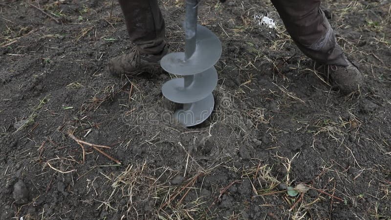 Handheld Footage with a Man Using a Hand Held Earth Hole Drilling ...