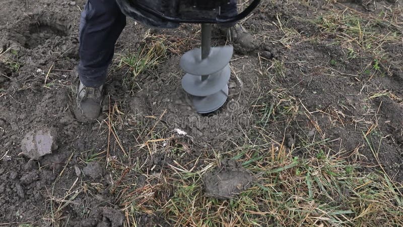 Handheld Footage with a Man Using a Hand Held Earth Hole Drilling ...