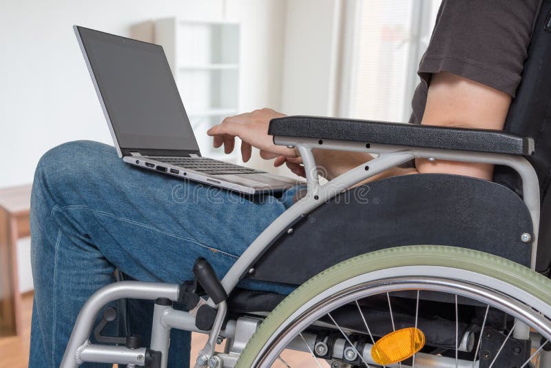 Handicapped Disabled Man On Wheelchair Is Working With Laptop In Office