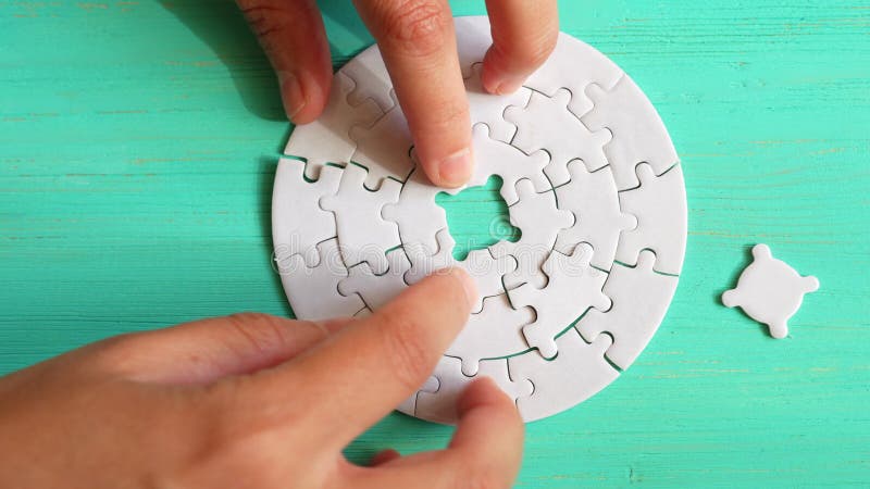 Hands Aligning and Inserting Final Puzzle Piece into Circular Design ...