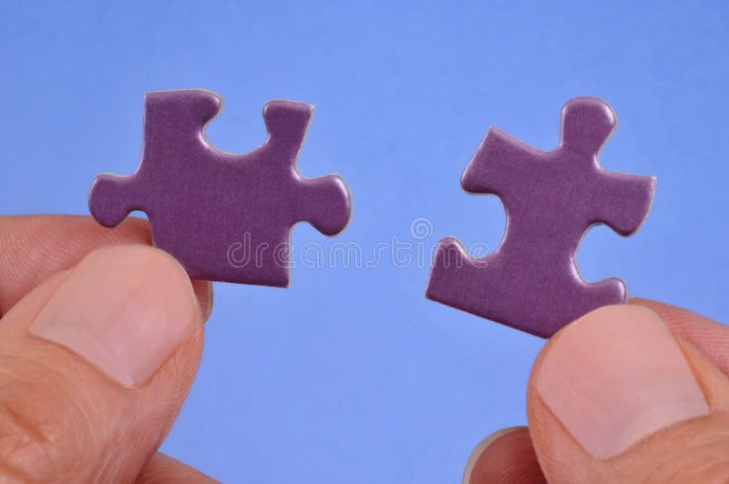 Hands Assembling Two Puzzle Pieces Close Up on Blue Background Stock ...