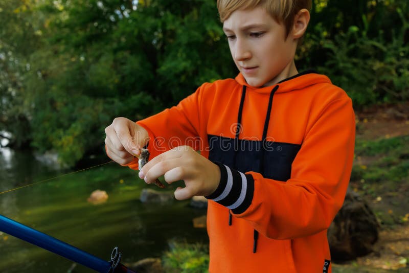 In the Hands of the Boy a Fishing Rod and a Fish that he Takes Off the ...