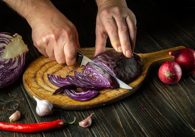 The Hands of the Chef are Cutting Red Cabbage on a Cutting Board with a ...