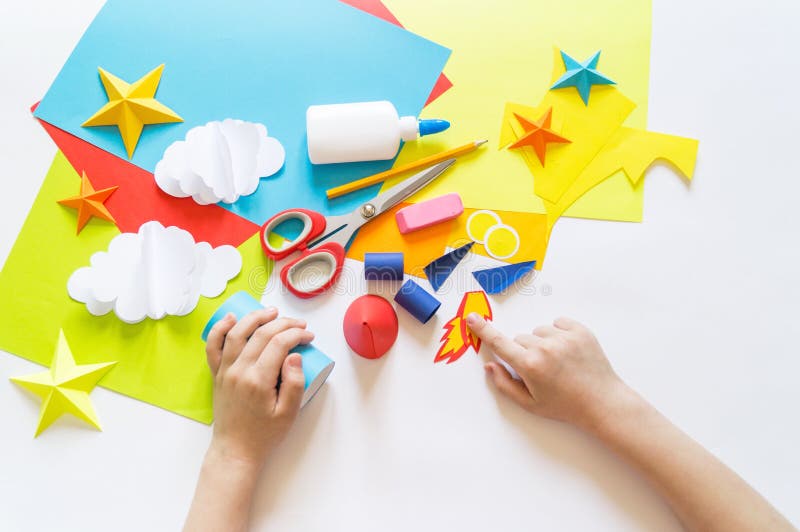 Hands of the Child Make a Paper Craft Rocket. Cosmos Clouds and Stars ...