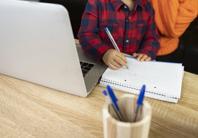 Hands of a Child Writing in a Notebook on a Desk at Home, with Laptop ...