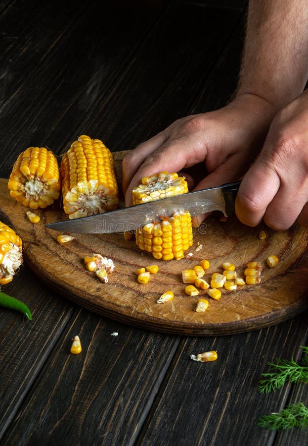 The Hands of the Cook with a Knife are Cutting Corn. Maize is an ...