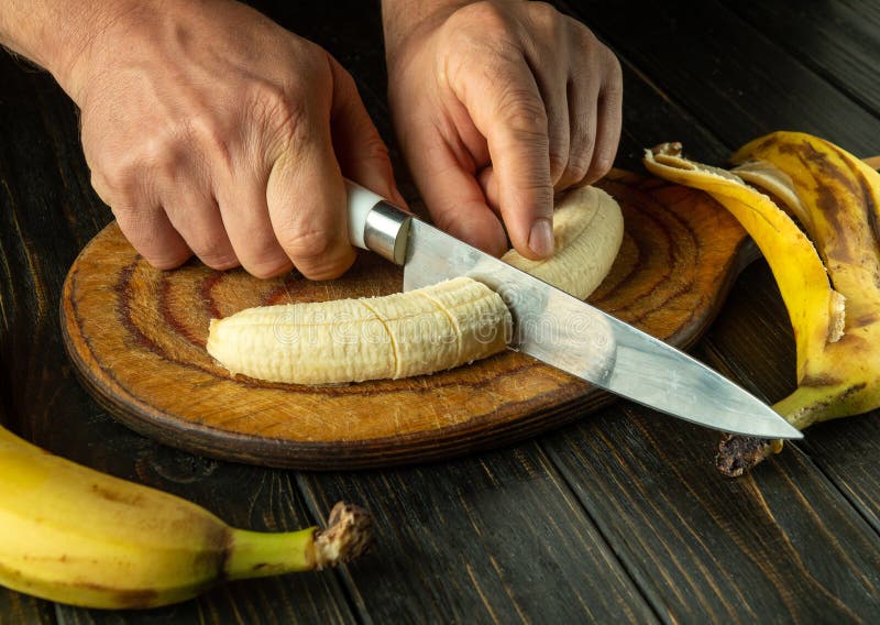 Hands of a Cook Using a Knife on a Kitchen Board Cutting a Ripe Banana ...