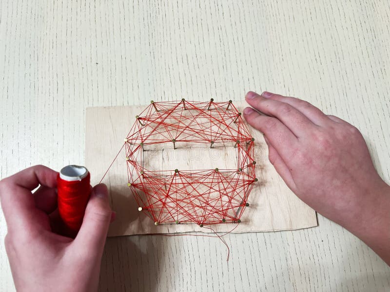 Hands Crafting Geometric String Art with Red Threads on a Wooden Board ...