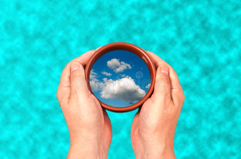 In the Hands of a Cup with a Reflection of Clouds on the Background of ...