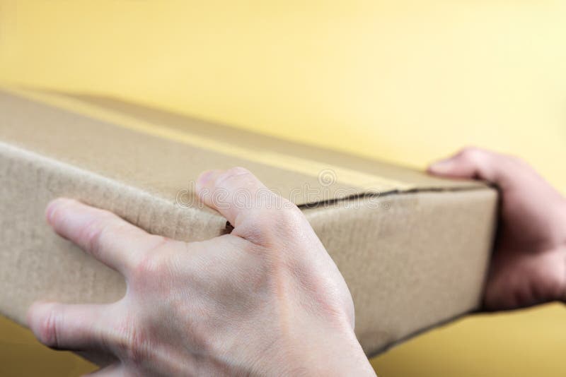 Hands of a Delivery Courier Hold an Empty Cardboard Box on a Yellow ...