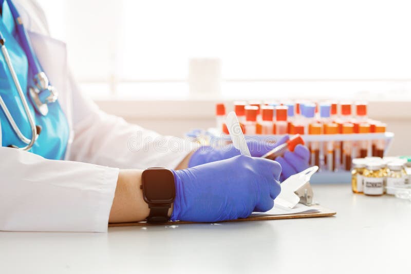 Hands of a Doctor Holding Blood Sample and Making Notes Stock Photo ...