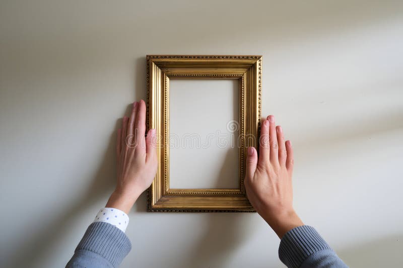 Hands Frame a Golden Picture Frame Against Neutral Wall, Radiating ...